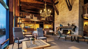 Um interior rústico com lareira, vigas de madeira e um candelabro.