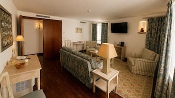 Uma sala de estar com sofá, cadeira, mesa, abajur, televisão e porta.