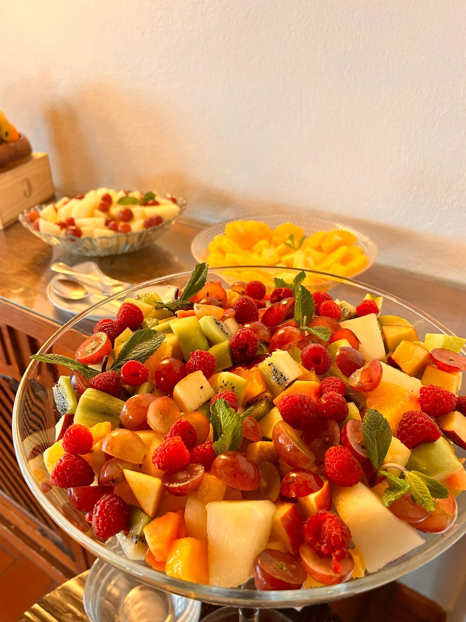 Salada de frutas variadas com folhas de hortelã em um prato de vidro.