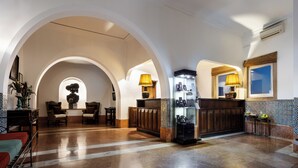 Um lobby com balcão de recepção, área de estar e um busto decorativo.