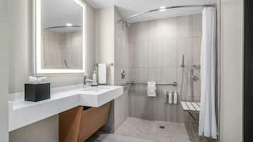 Uma casa de banho moderna com cabine de duche, um espelho grande e toucador com porta-toalhas.