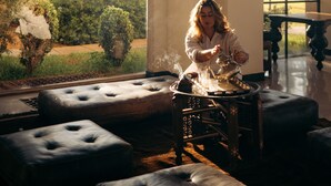 Um quarto com grandes janelas em arco, uma mesa com um bule e um sofá.