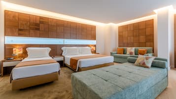 Quarto de hotel com duas camas, um sofá, painel de cabeceira em madeira e piso coberto por carpete.
