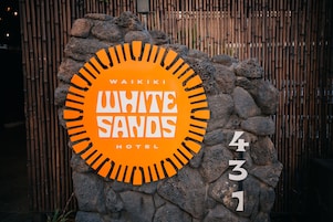Placa do Hotel Waikiki White Sands, com design circular exibindo o nome e endereço do hotel.