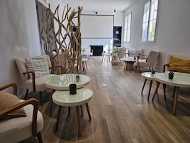 Uma área de lounge moderna com mesas redondas, assentos confortáveis e lareira.