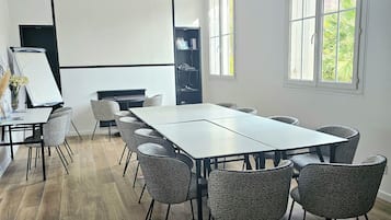 Uma sala de conferências com uma mesa comprida, cadeiras, um projetor e uma tela.