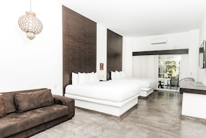 Quarto de hotel moderno com uma cama grande, um sofá, um espaço de refeições e vista para o exterior.