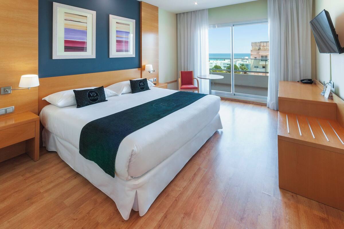 Quarto de hotel com uma cama grande, uma escrivaninha, uma cadeira e vista para a cidade.