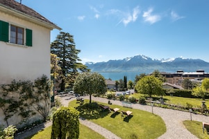 Zona residencial com casa, jardim bem cuidado e vista para montanhas e lago.