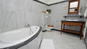 Uma casa de banho com banheira, sanita, lavatório e espelho.