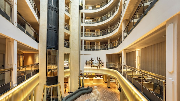 Um átrio em vários níveis com uma escadaria espiral central, várias varandas e um imponente candelabro.