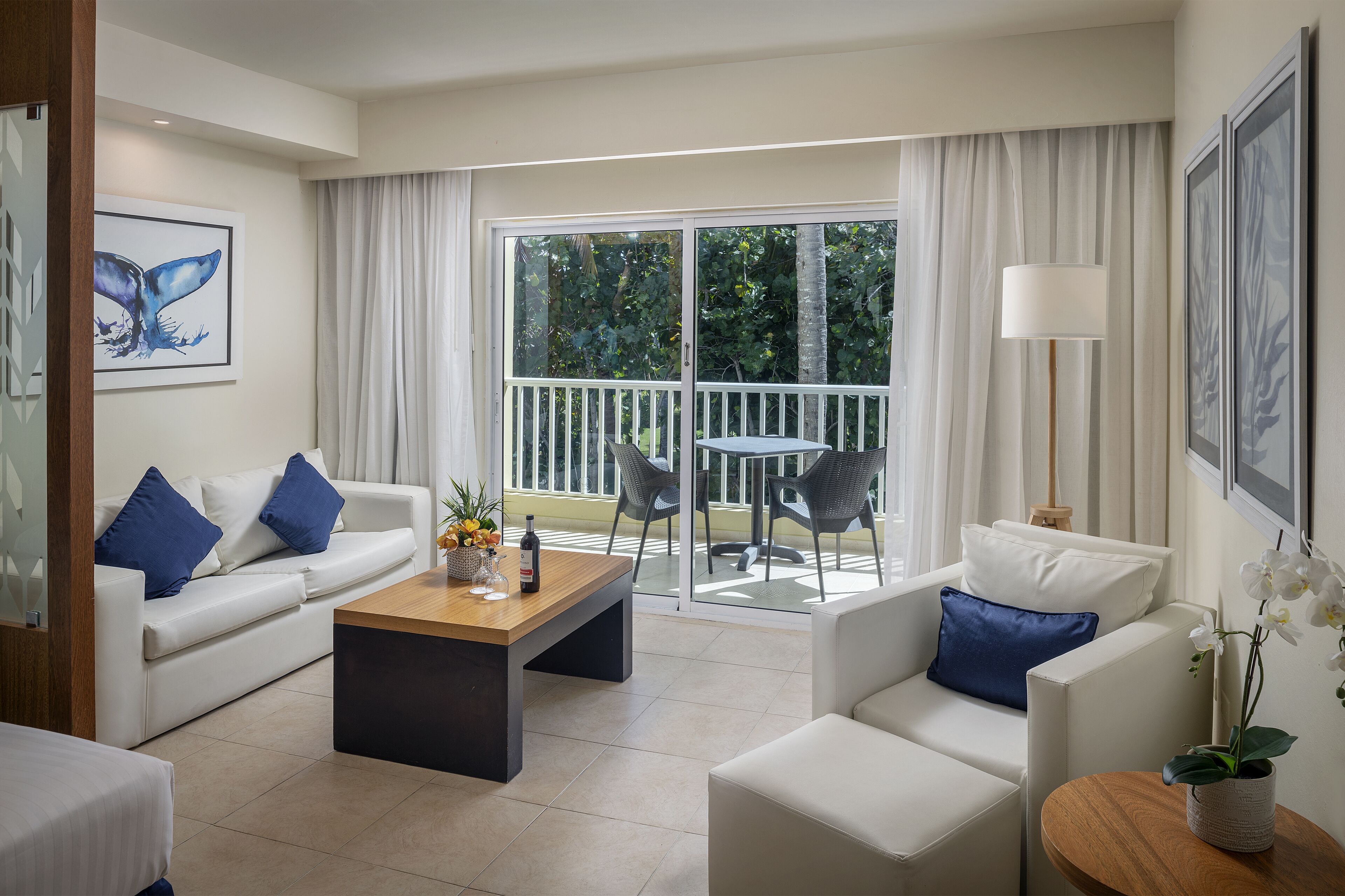 Uma sala de estar moderna com um sofá branco, uma mesa de centro de madeira e uma varanda com porta de vidro.