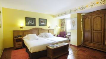 Quarto de hotel com cama de casal, mesa de cabeceira de madeira, uma cadeira, guarda-roupa e tapete vermelho.