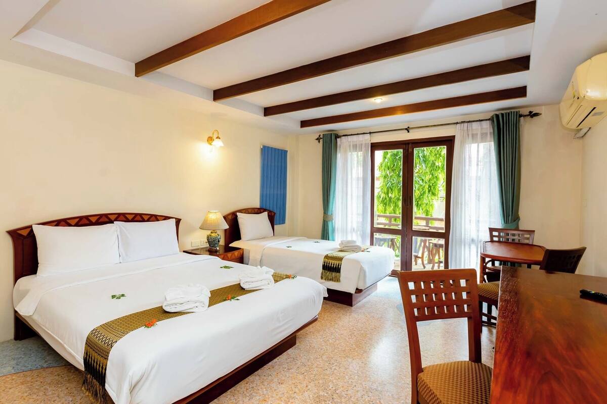 Quarto de hotel com duas camas, uma escrivaninha e uma cadeira.