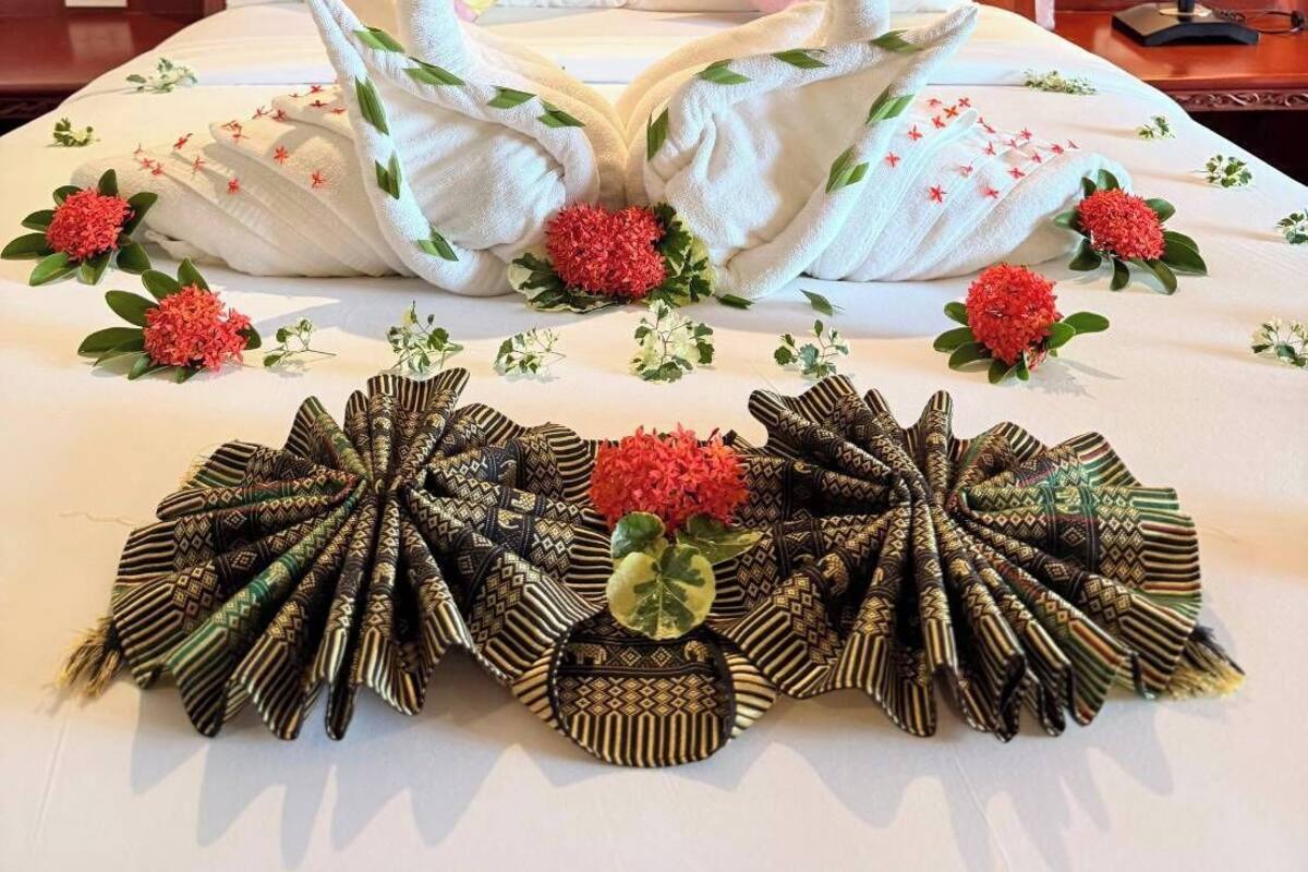 Uma cama com cabeceira decorativa, almofadas e um arranjo floral.