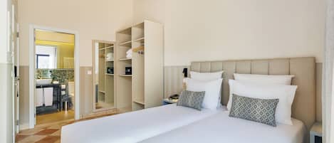 Quarto espaçoso com uma cama grande, um guarda-roupa e um banheiro visível através de uma porta aberta.