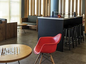 Uma área de bar moderna com mesa de bilhar, cadeiras vermelhas e balcão com banquetas.