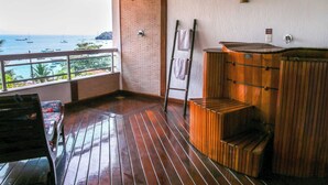 Um deck de madeira com vista para o mar, uma sauna e um banco.