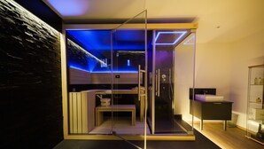 Um banheiro moderno com box de vidro, um banco de madeira e uma área de pia minimalista.