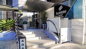Entrada do Hotel Slaviere, com design moderno, incluindo uma escadaria e uma placa.