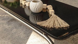 Uma sala de estar moderna com um sofá de couro preto, uma mesa de centro com objetos decorativos e uma planta em vaso.