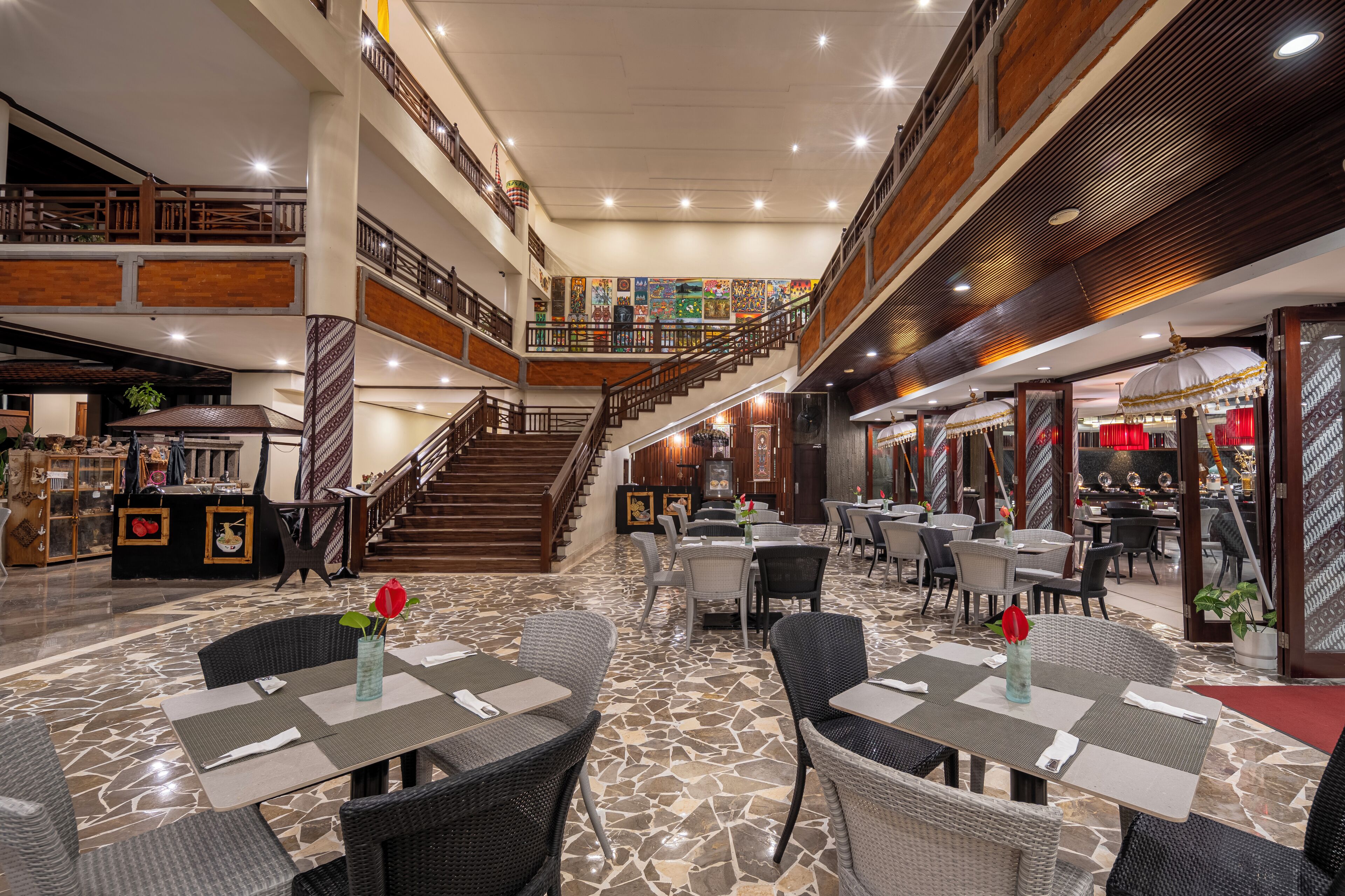 Um hall de hotel amplo em vários níveis, com escadaria, área de refeições e bar.