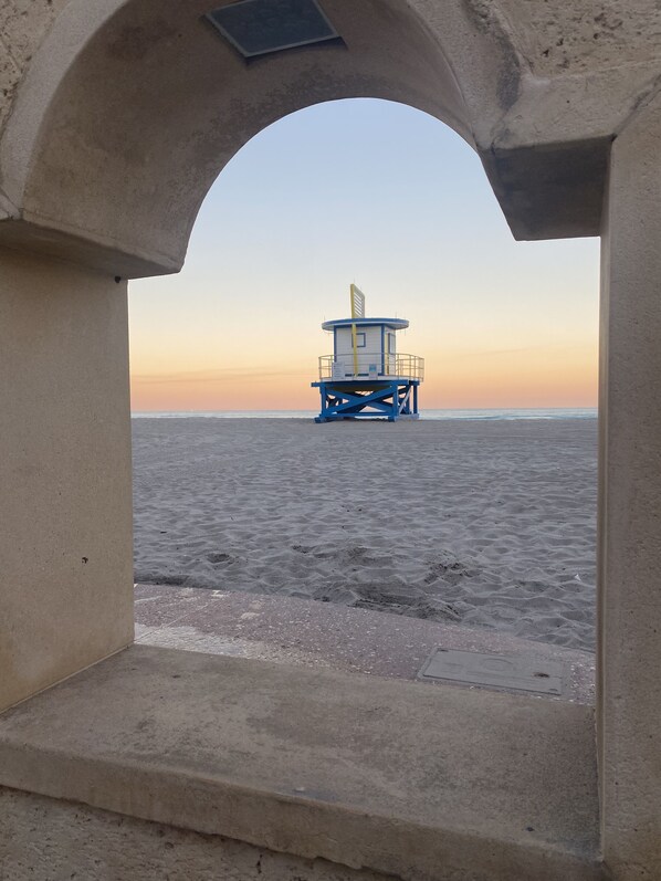 Uma torre de salva-vidas numa praia, vista através de um arco.