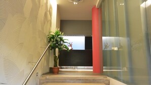 Uma escadaria com uma planta em vaso, um pilar vermelho e um design moderno na parede.