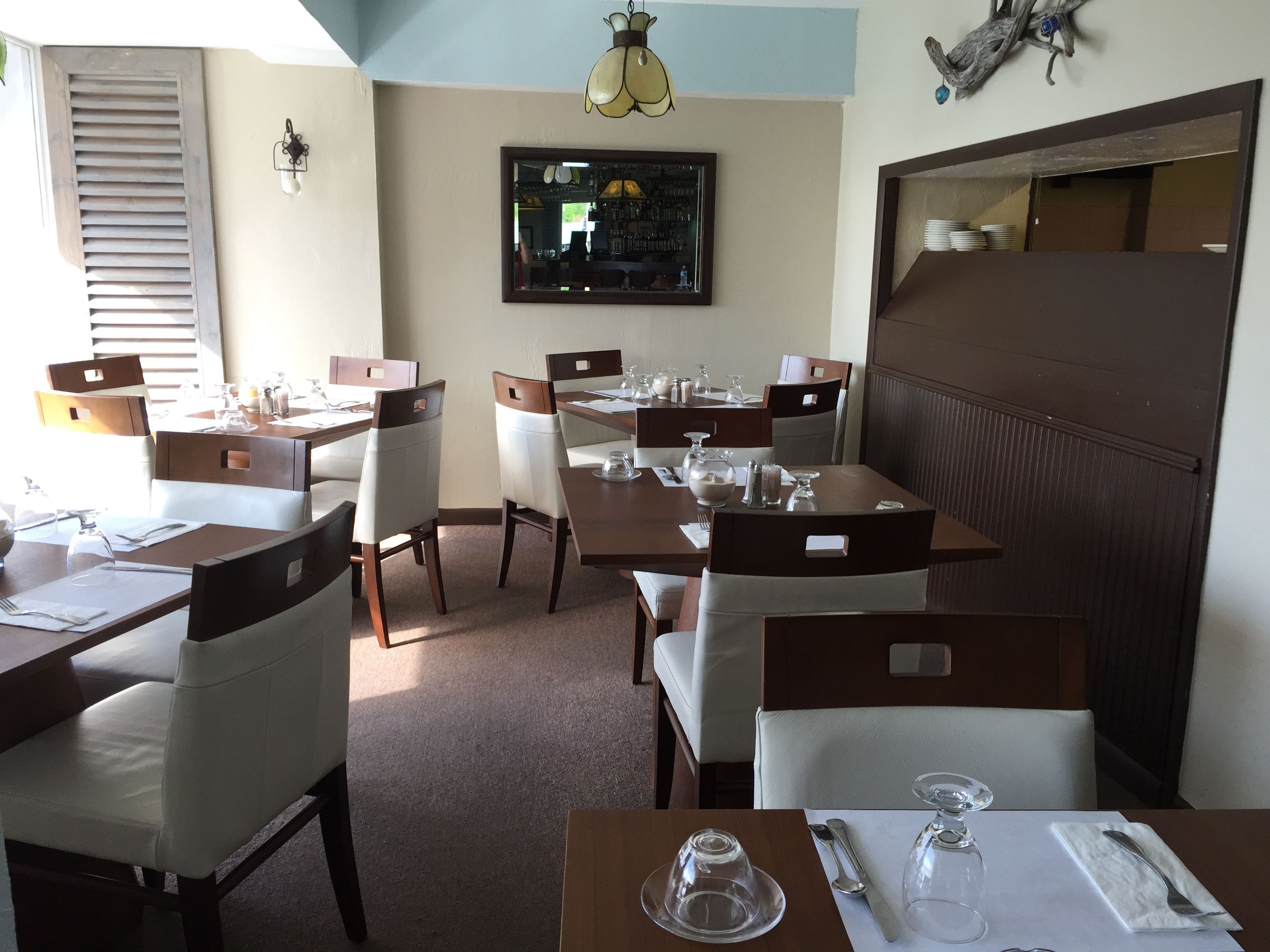 Um restaurante com várias mesas e cadeiras, um espaço de bar e um quadro pendurado na parede.