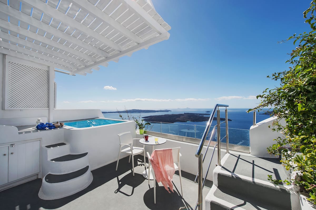Uma varanda com piscina, mobiliário branco e vista para o mar.