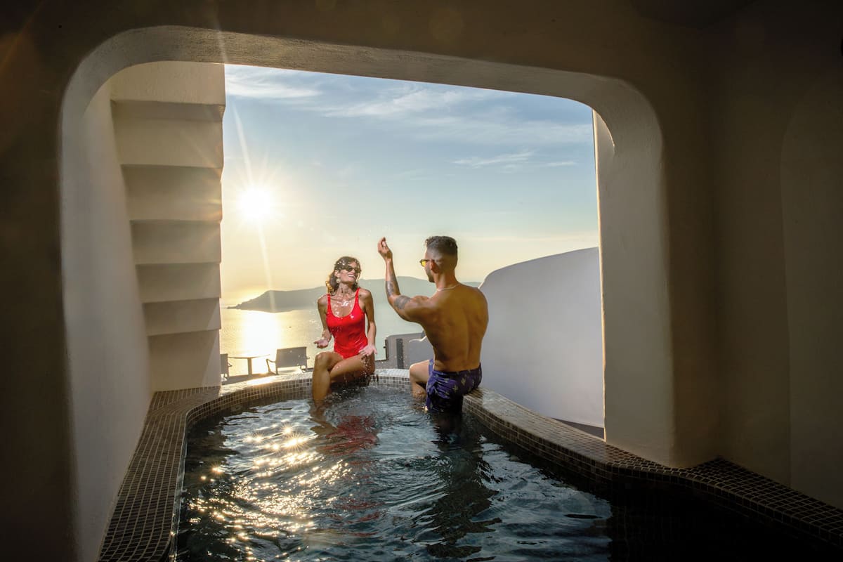 Um casal em uma banheira de hidromassagem com vista para o pôr do sol.