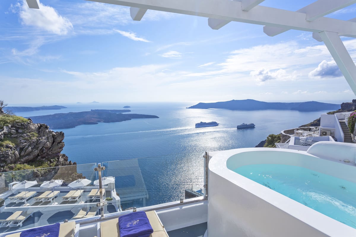 Uma varanda luxuosa com vista clara para o mar, uma piscina e espreguiçadeiras.