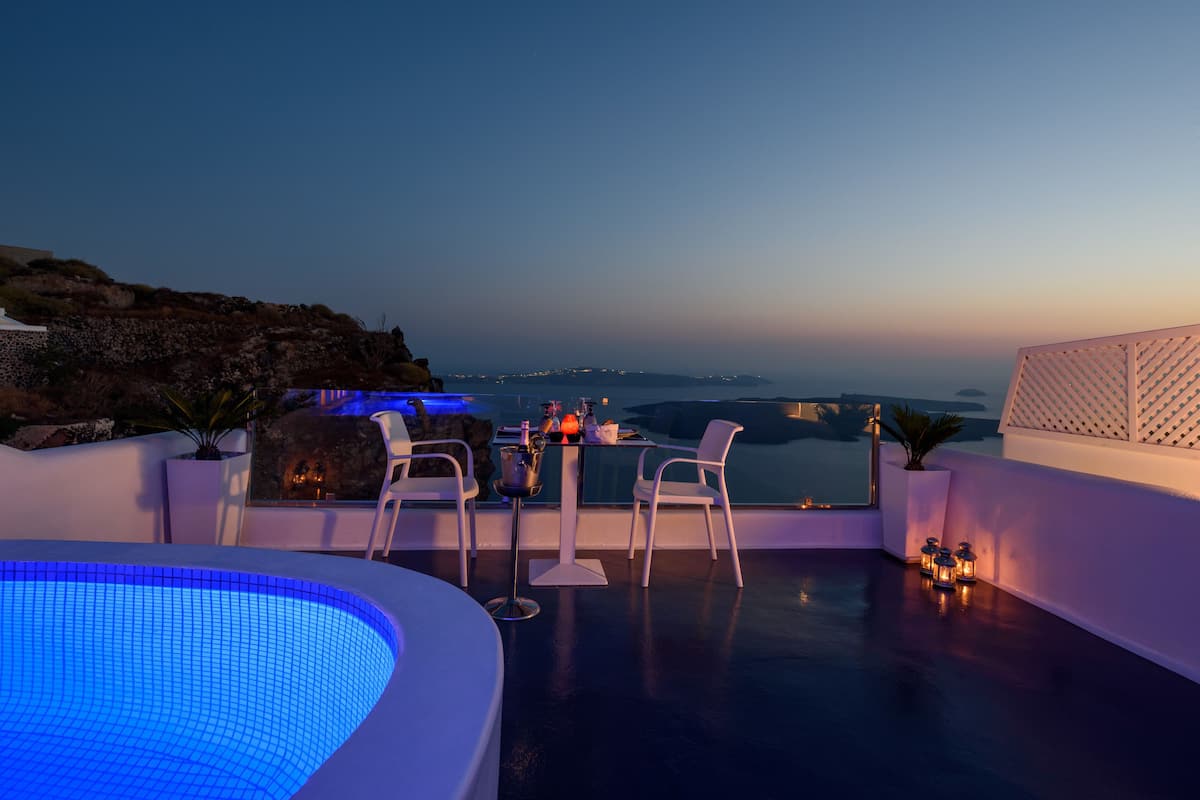 Uma área de piscina no terraço com vista para o mar, uma mesa com cadeiras e um pequeno jardim.