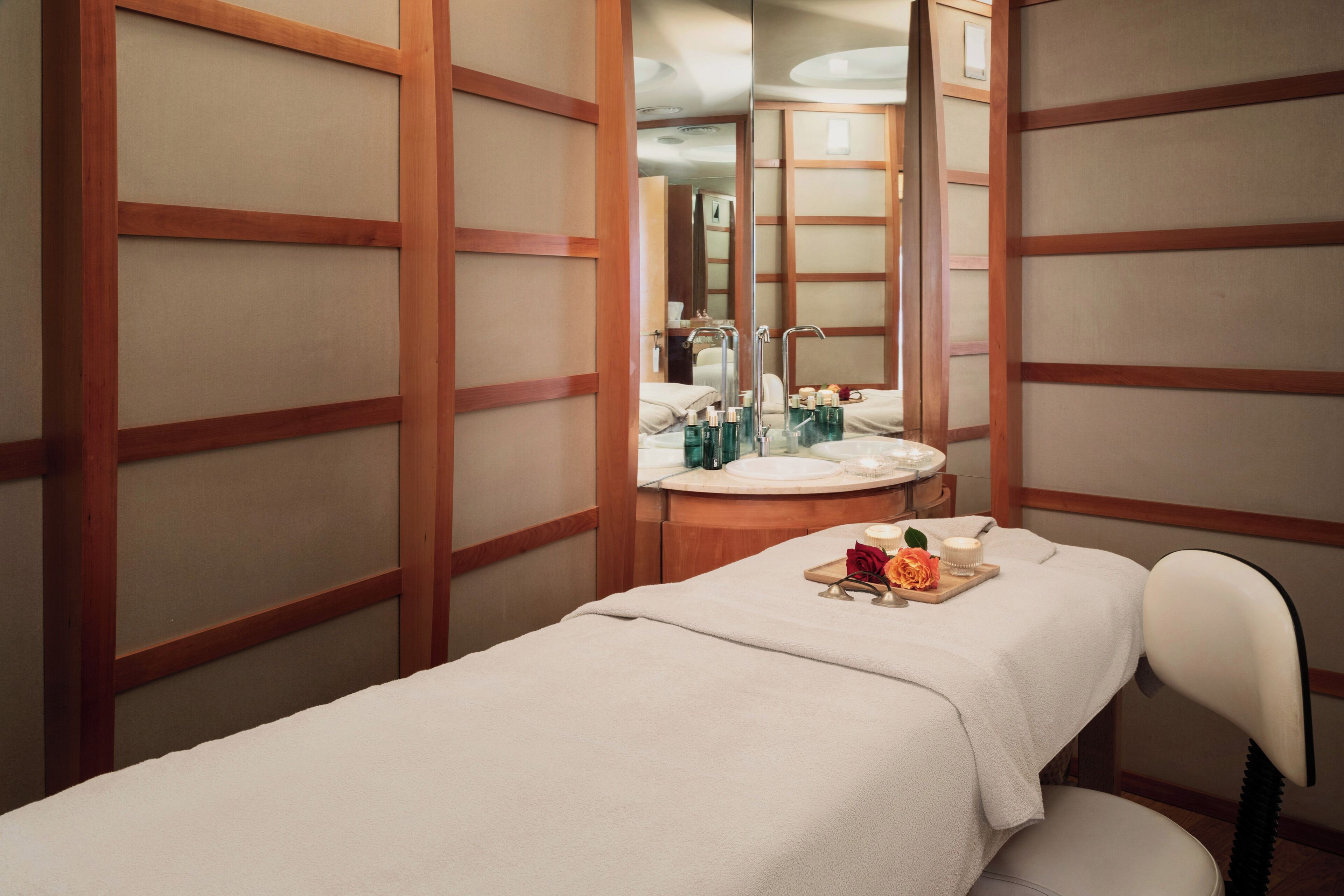 Um quarto de spa com uma cama, espelho, pia e artigos de higiene pessoal.
