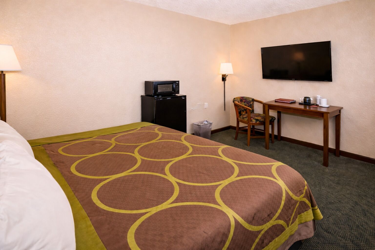 Quarto de hotel com cama, escrivaninha, televisão e máquina de café.