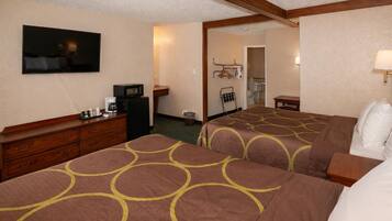 Quarto de hotel com duas camas, um armário, uma televisão e uma pequena cozinha.