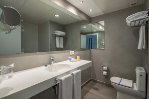 Uma casa de banho moderna com um espelho grande, uma pia e uma sanita.