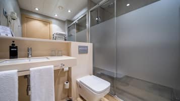 Casa de banho moderna com lavatório, sanita e cabine de duche em vidro.