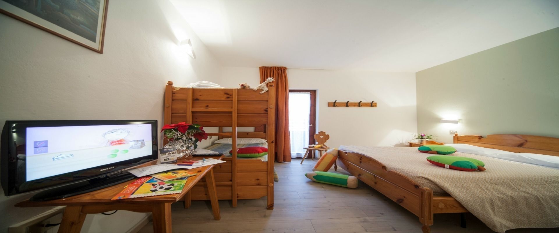 Um quarto com beliche, escrivaninha com computador e televisão.