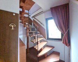 Escadaria com degraus de madeira e corrimão de metal que dá acesso a um andar superior.