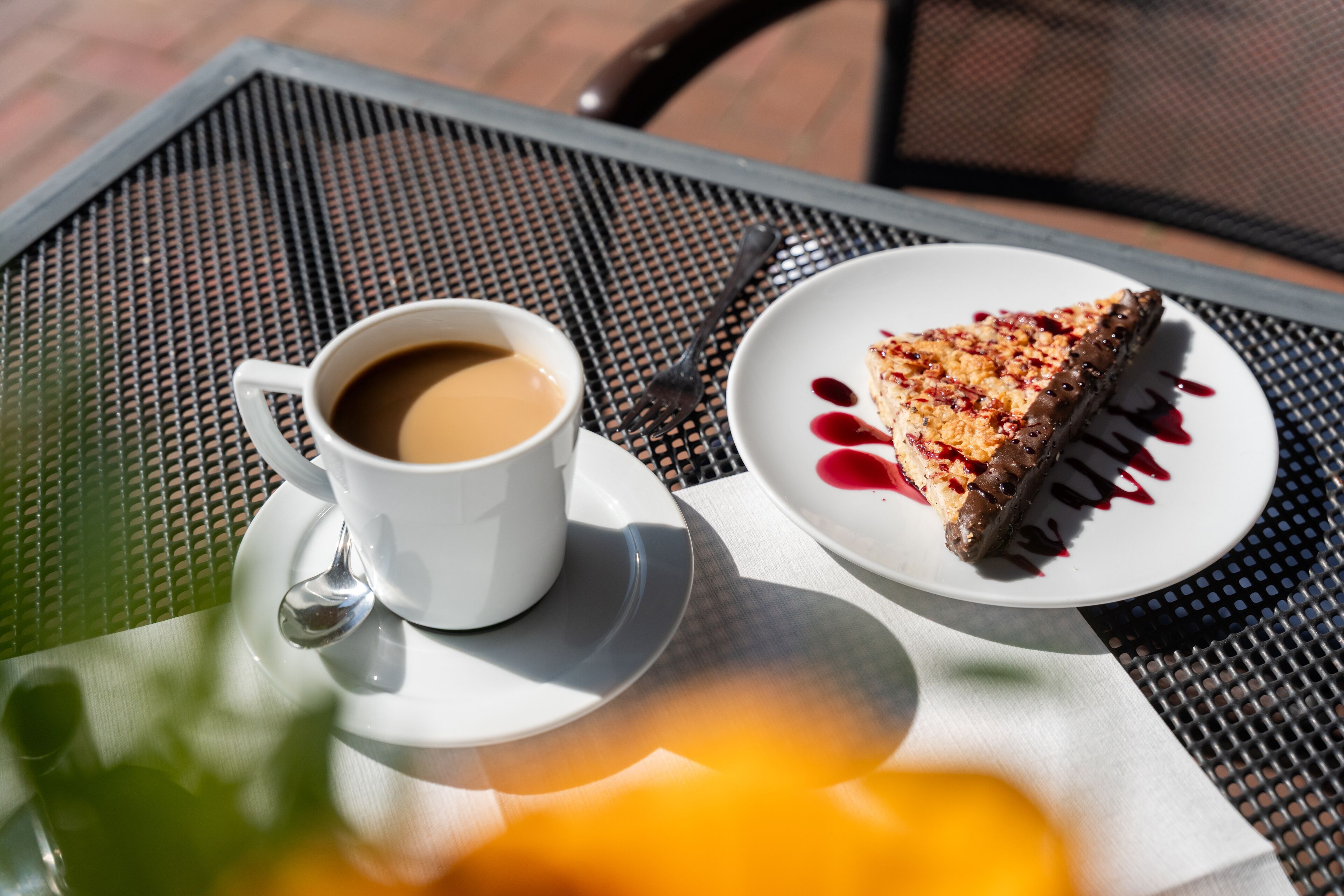Uma mesa com uma xícara de café e uma fatia de torta sobre uma mesa de metal.