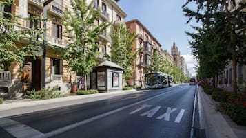 Rua com faixa para táxis, edifícios com varandas e um ônibus.