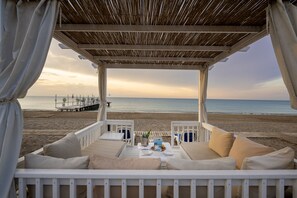 Uma área de estar à beira-mar com vista para o oceano, um píer e uma mesa posta para refeições.