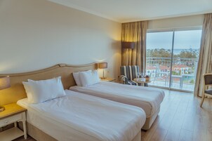 Quarto de hotel com duas camas, varanda e vista para prédios.