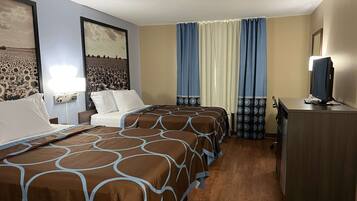 Quarto de hotel com duas camas, uma mesa, televisão e janela com cortinas.