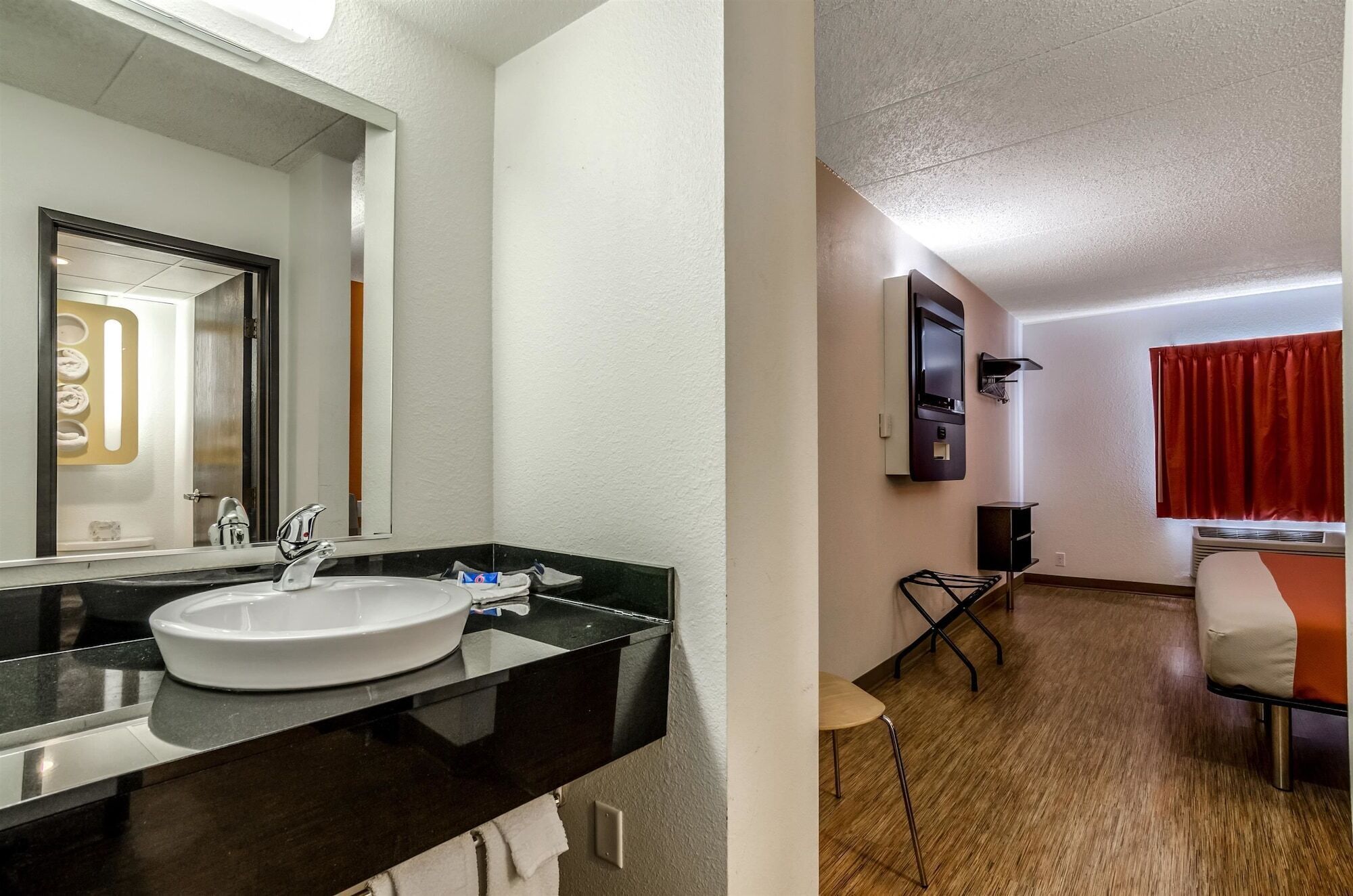 Uma casa de banho moderna com um espelho grande, uma sanita branca e bancada preta.