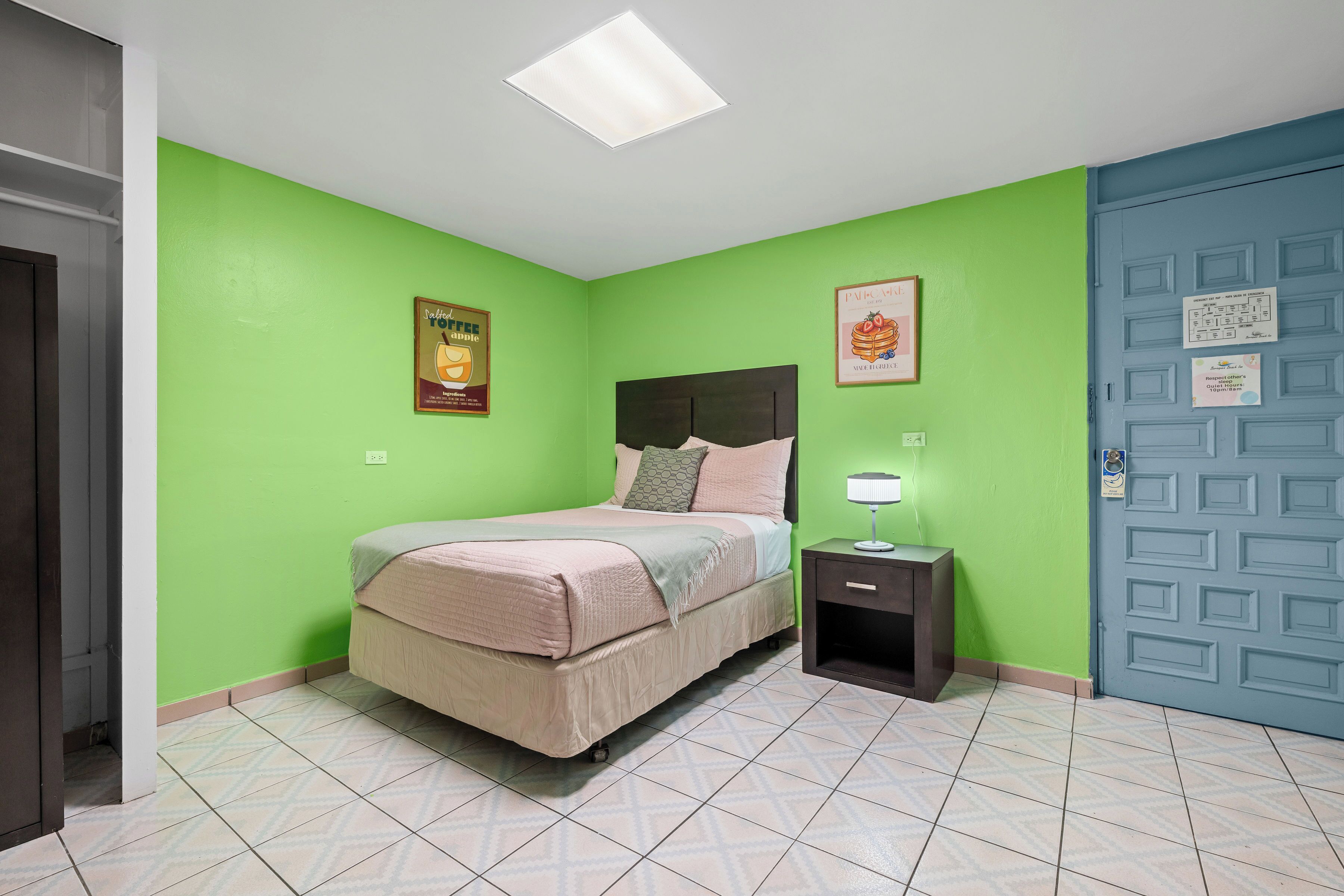 Quarto com cama, mesa de cabeceira e porta azul.