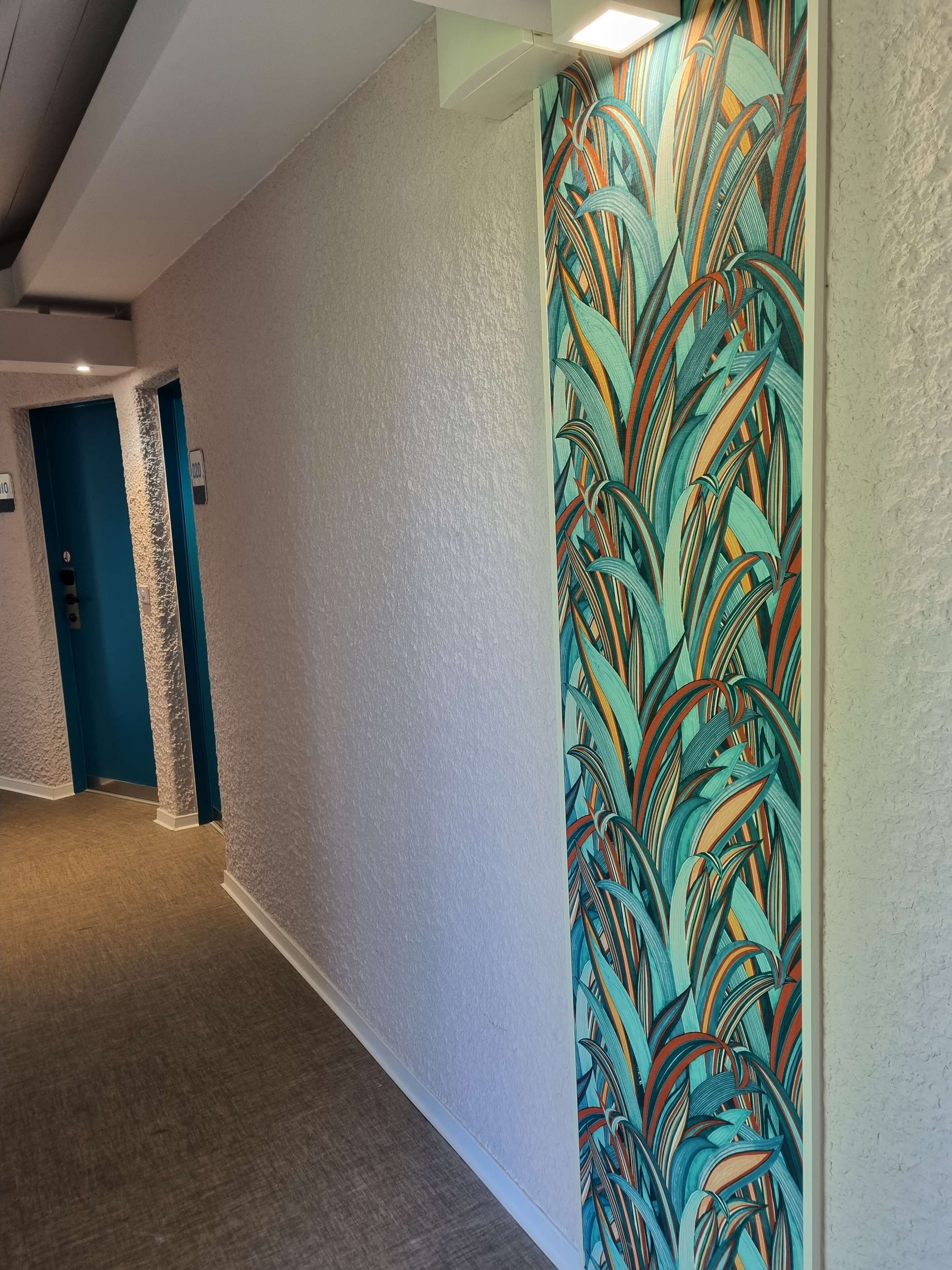 Um corredor com paredes texturizadas, um mural padronizado e portas azuis.