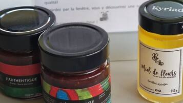 Três potes de mel com etiquetas, colocados sobre uma mesa com um letreiro sobre compotas locais e originais.