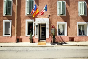 Entrada de hotel com uma placa indicando "HOTEL PLAZA" e bandeiras.